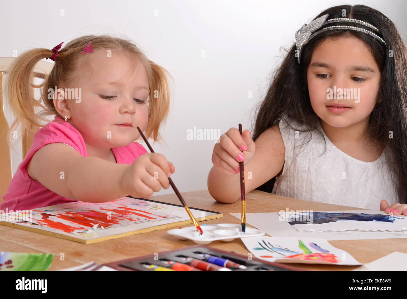 Two girls painting at a table Stock Photo - Alamy