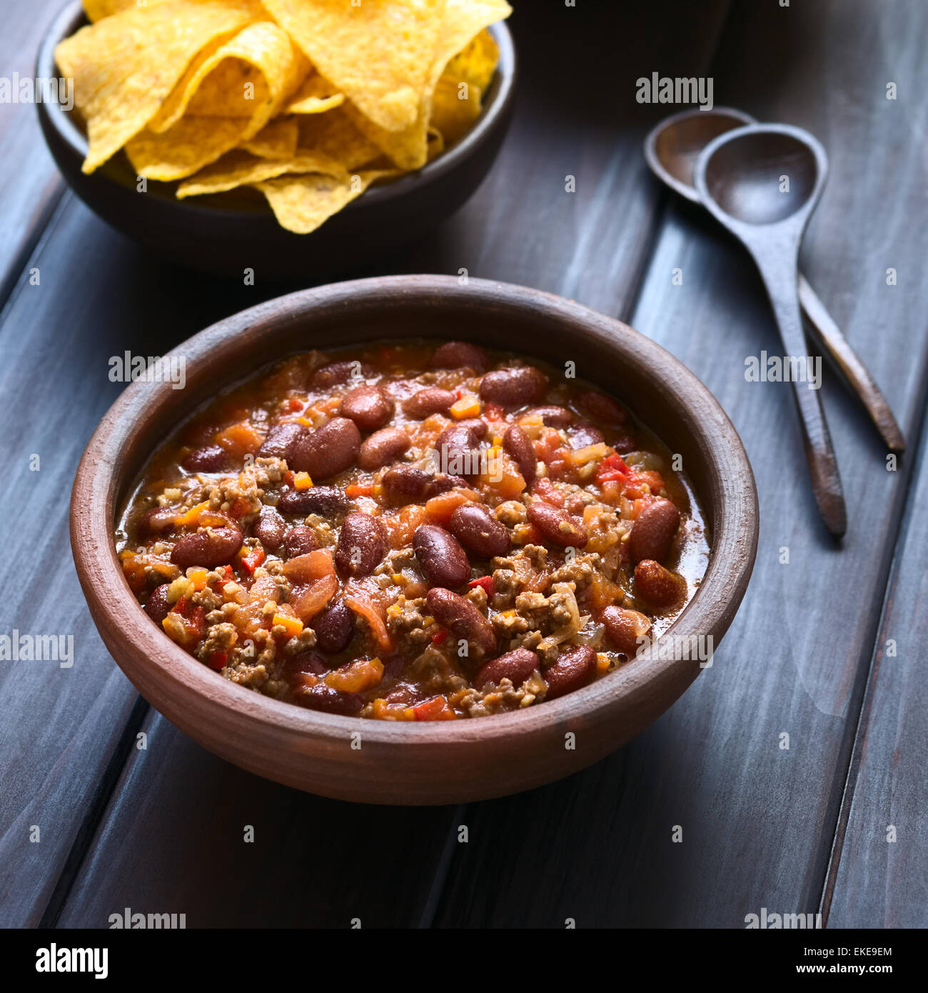 Rustic bowl of chili con carne with tortilla chips in the back ...