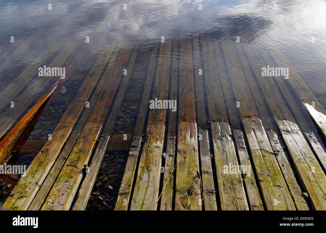Wooden ramp used for putting boats into sea and the sky reflecting in ...