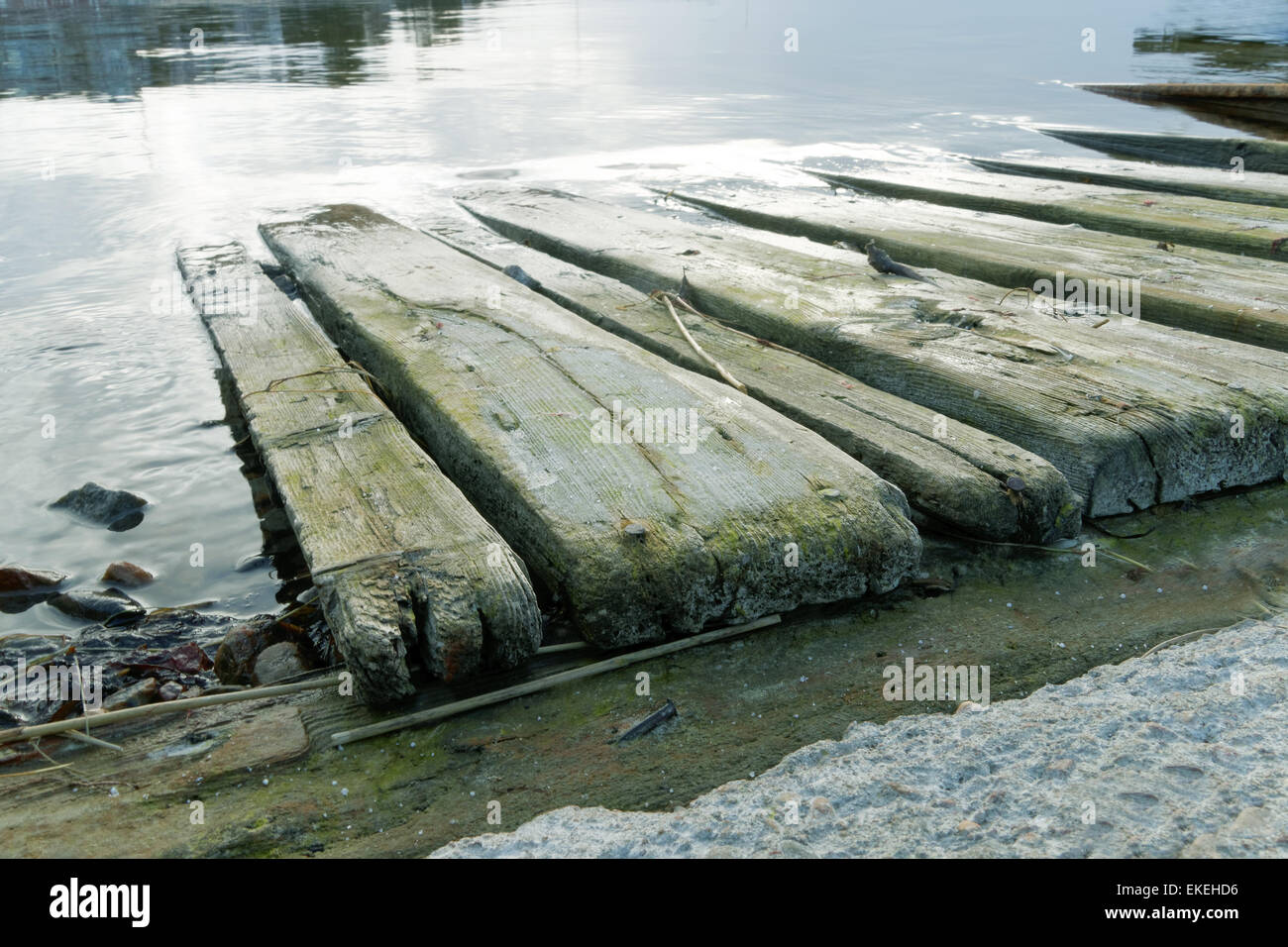 Wooden ramp used for putting boats into sea and the sky reflecting in ...