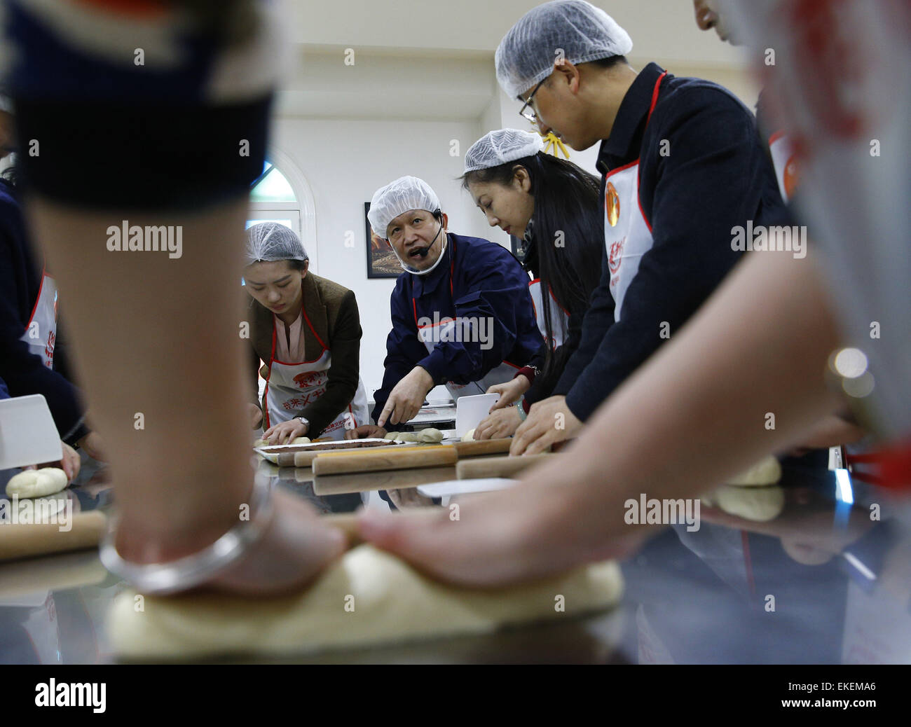 Beijing, China. 9th Apr, 2015. A staff member (3rd R) teaches people to ...