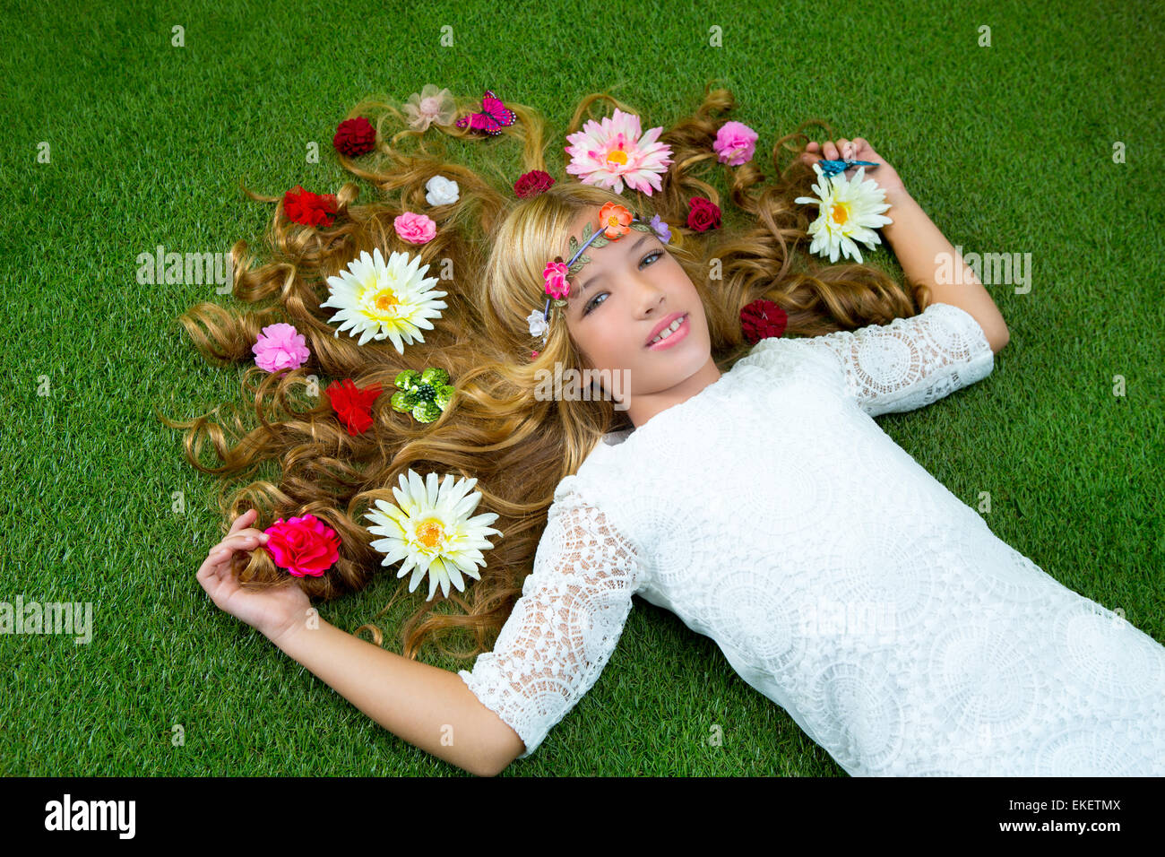 Blond spring girl with flowers on hair over grass Stock Photo - Alamy