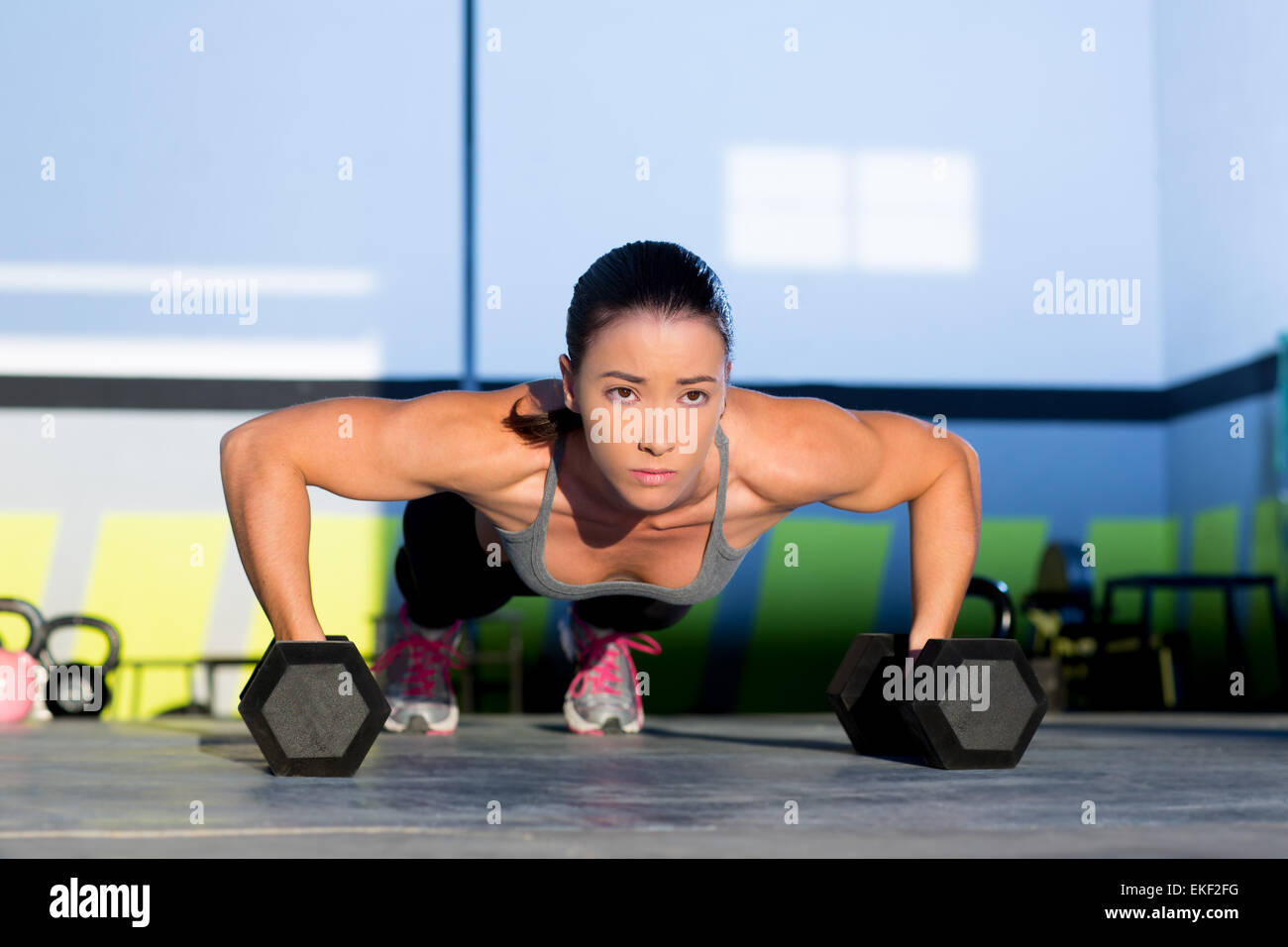 Gym woman push-up strength pushup with dumbbell Stock Photo - Alamy