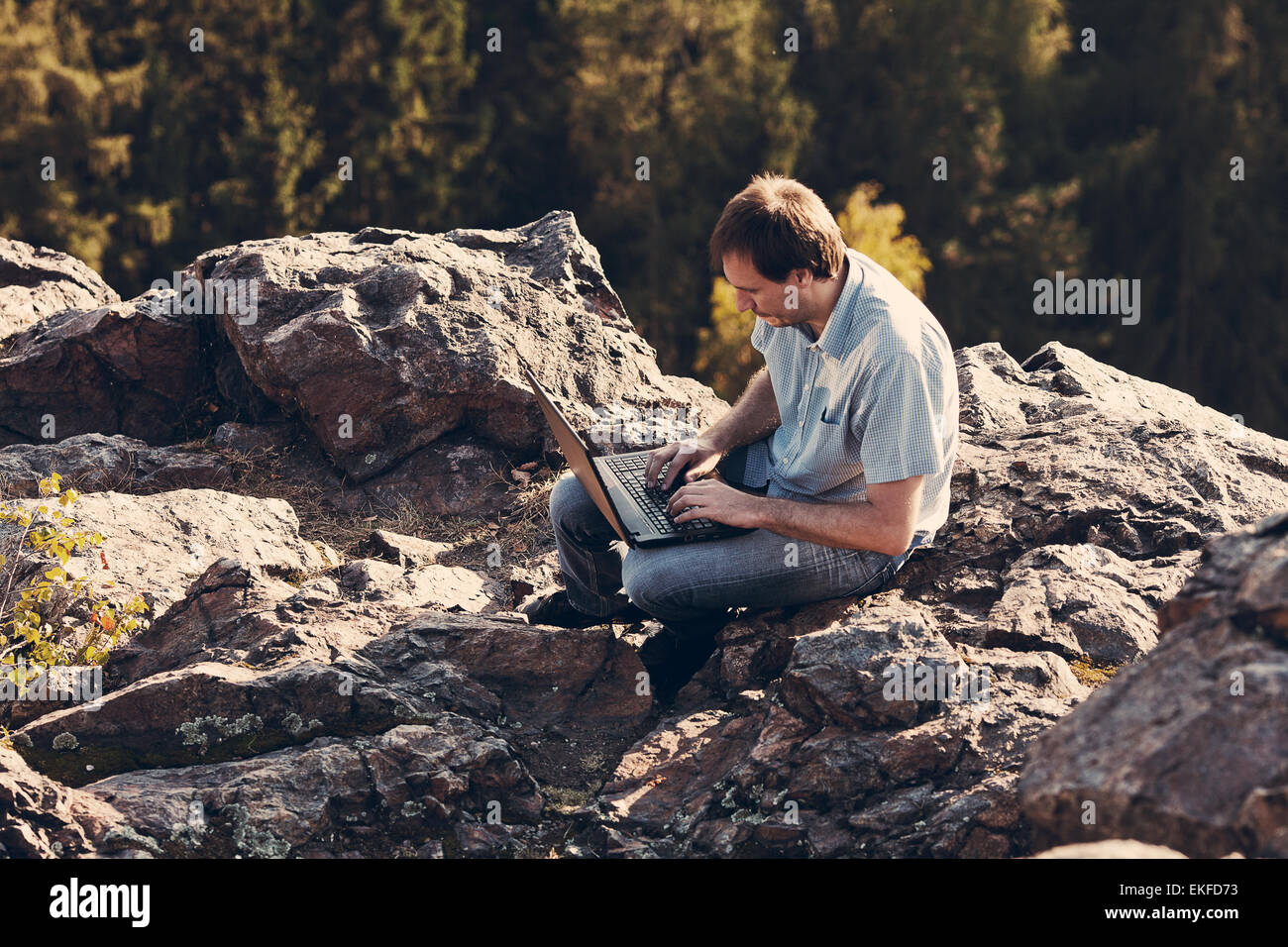 young man using laptop sitting on a rock slope Stock Photo - Alamy
