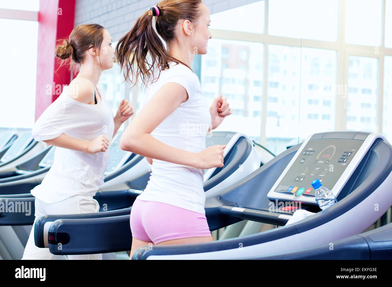 Two young sporty women run on machine Stock Photo - Alamy