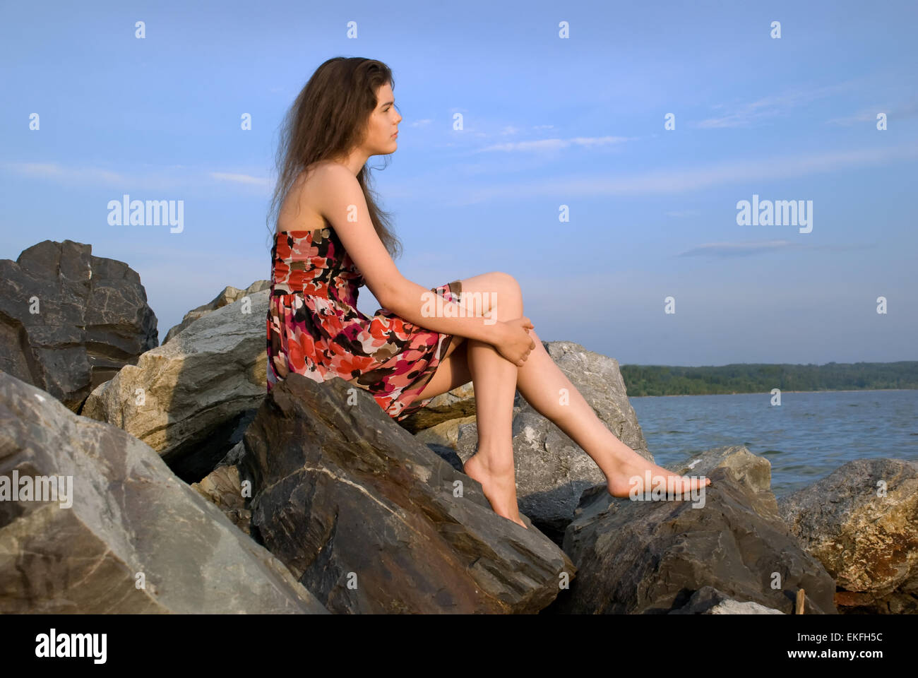 Beautiful girl sit on rock on sea coast Stock Photo - Alamy