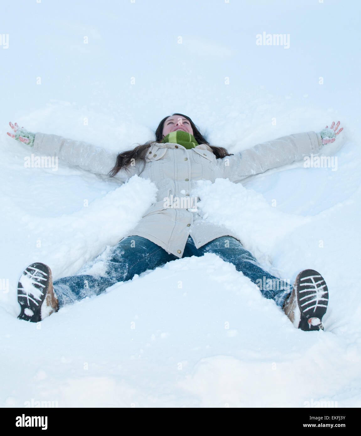 Beautiful girl in green lying in snow Stock Photo - Alamy