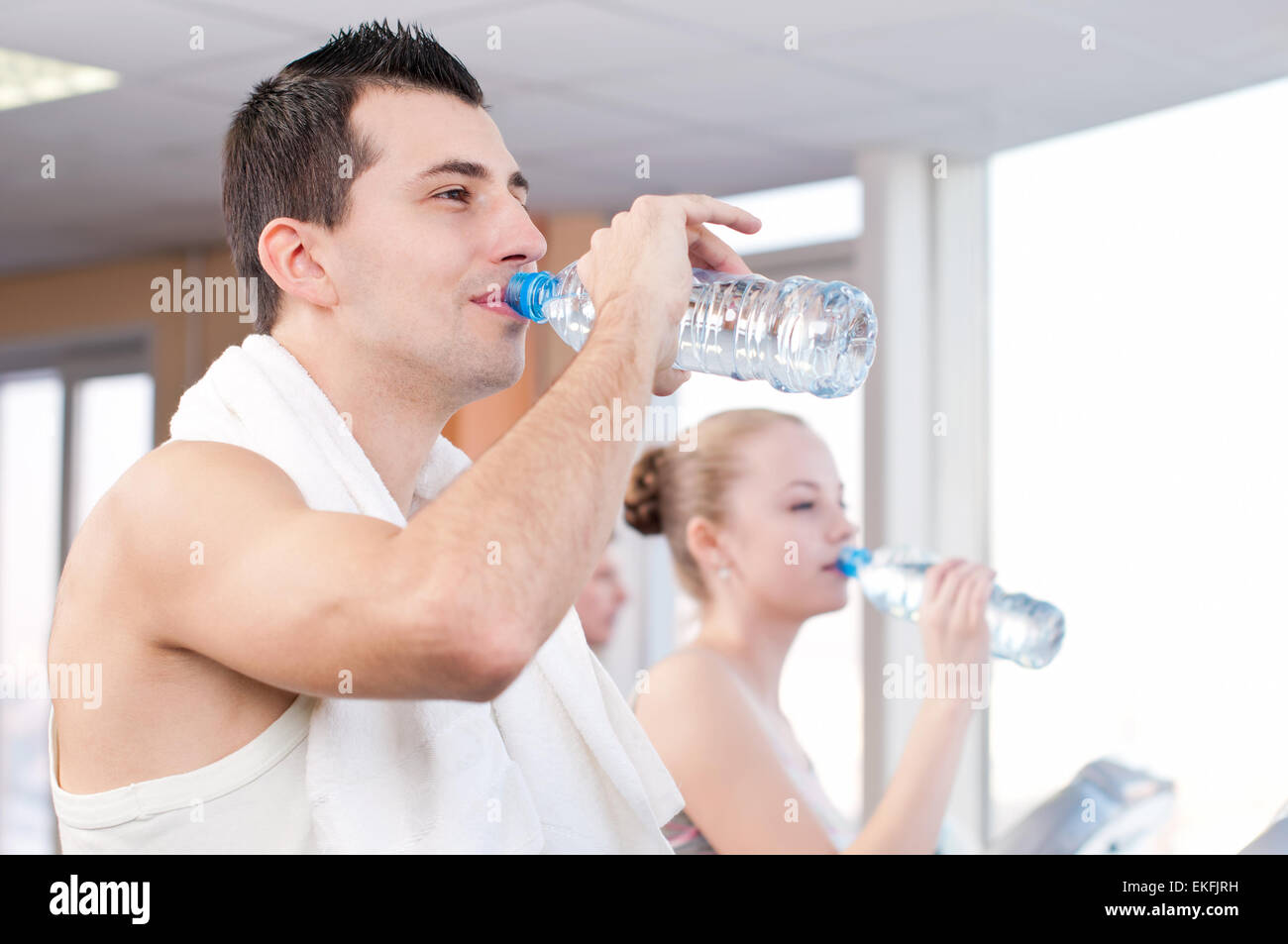 Man and woman drinking water after sports in gym Stock Photo - Alamy