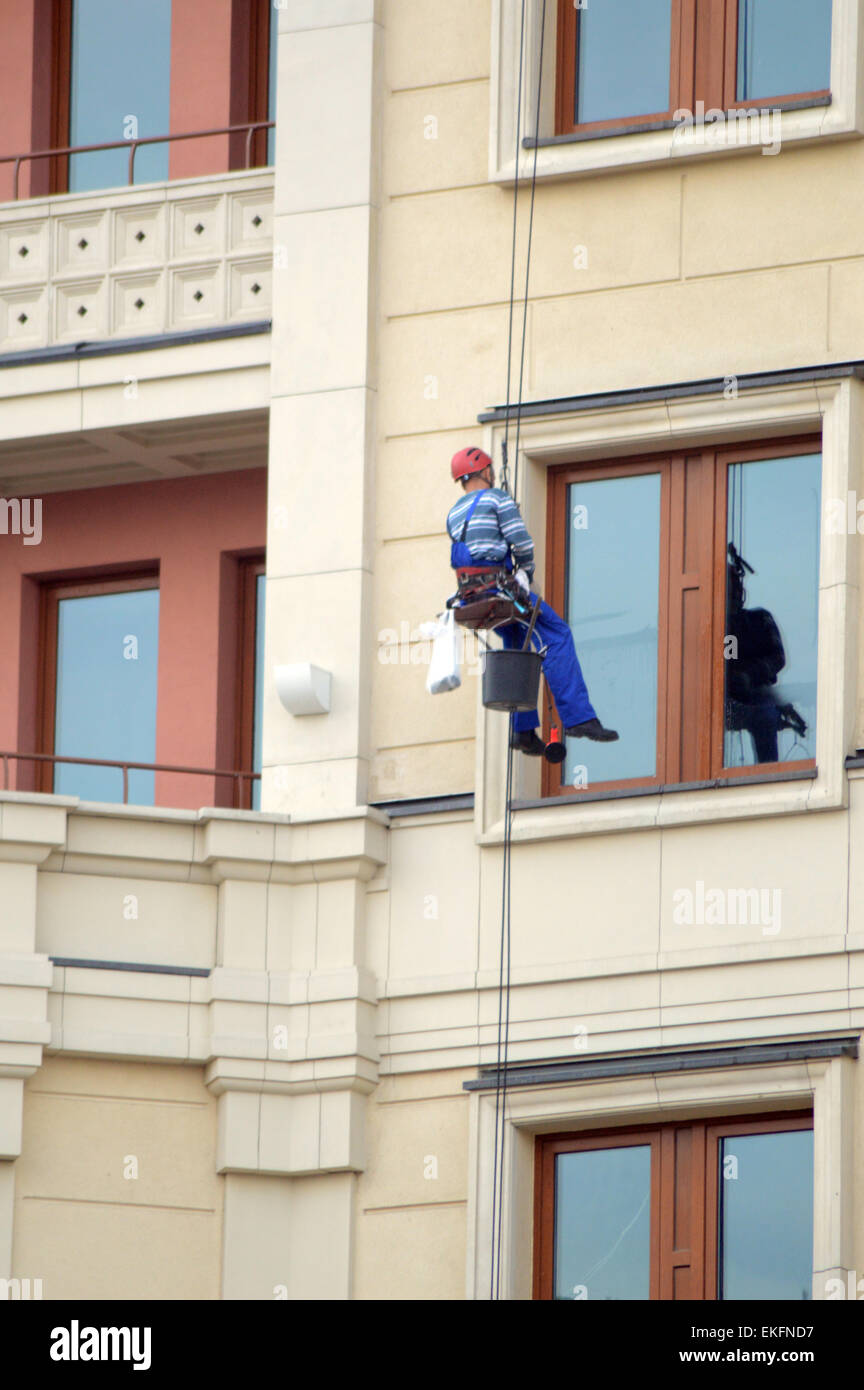 Man in special clothes washing windows on high-rise building Stock ...