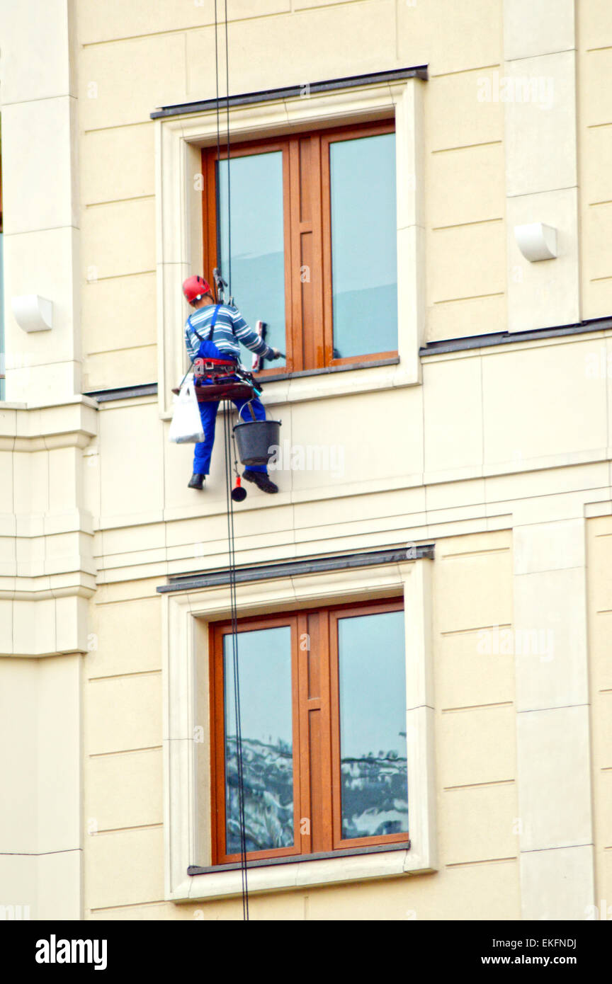 Man in special clothes washing windows on high rise building detergent ...