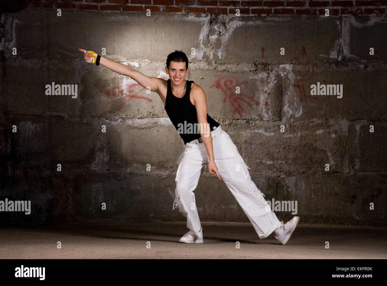 Hip hop boy dancing in modern style over grey brick wall Stock Photo ...