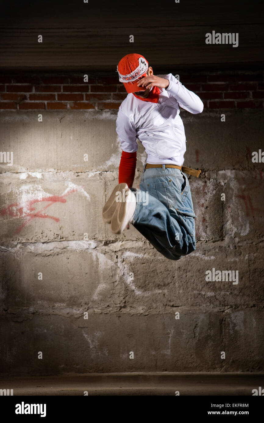 Hip hop boy dancing in modern style over grey brick wall Stock Photo ...