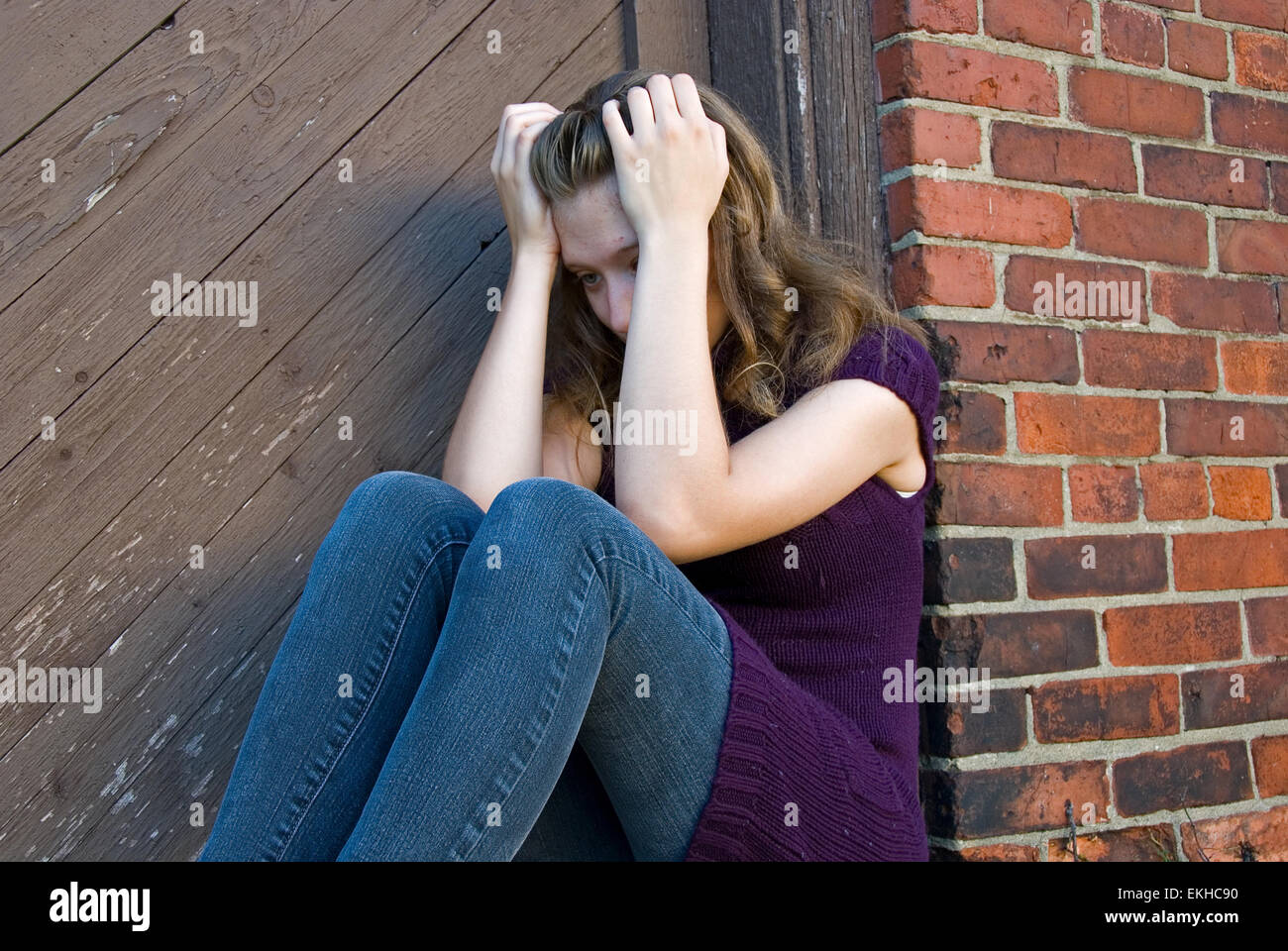 Teenage girl huddles in despair in a doorway Stock Photo - Alamy