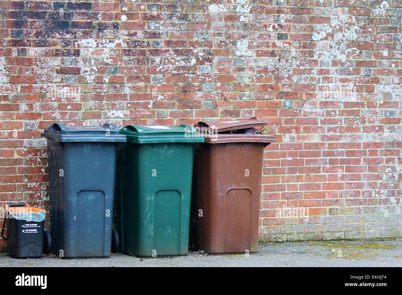 dustbins trash can outside against brick wall Stock Photo - Alamy