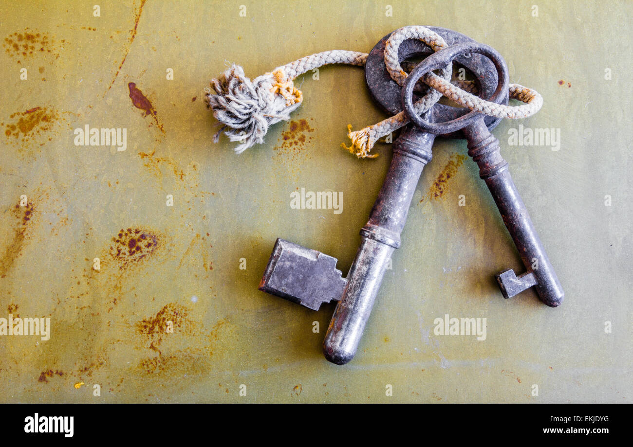 Two ancient vintage keys tied with frayed string on grungy metal ...