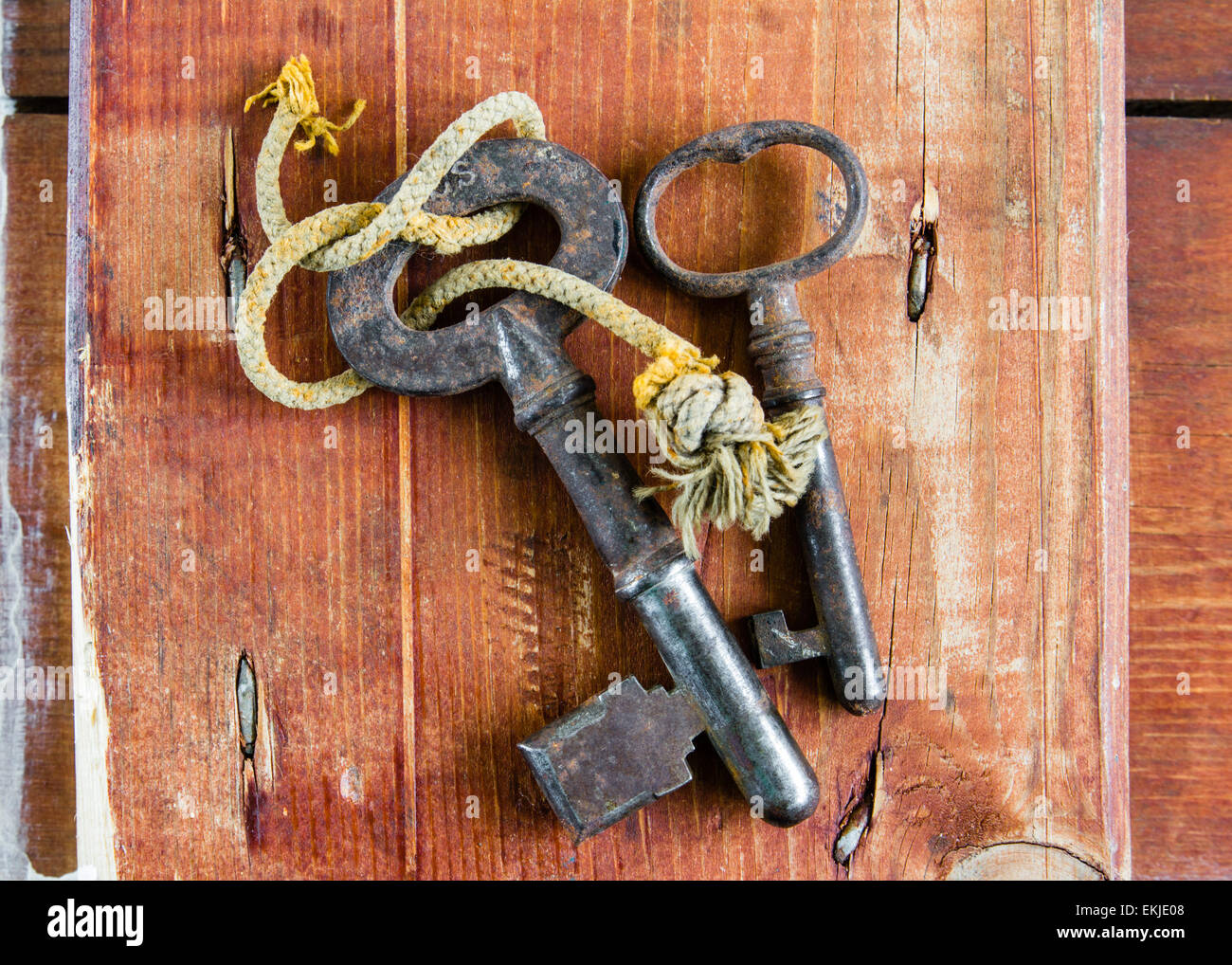 Two ancient vintage keys with frayed string on grungy wood background ...