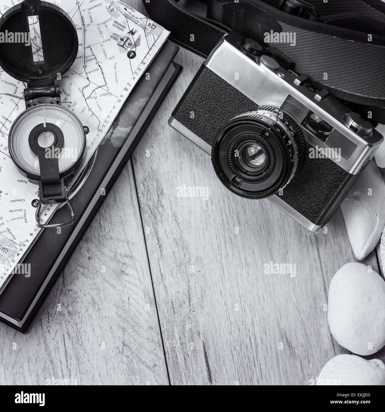 In the picture an analog camera film , a compass,book and a map, on the ...