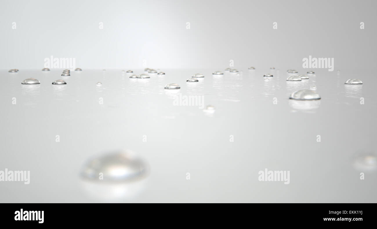 A collection of various size droplets of water on a reflective white ...