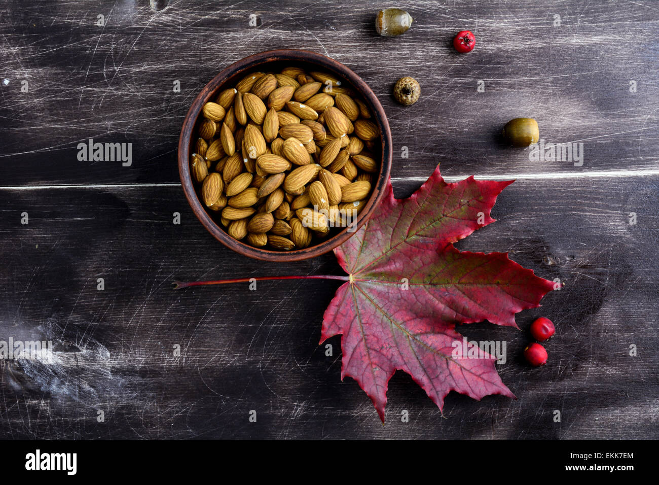 Fall background: raw almonds in bowl and red maple leaf on rustic ...