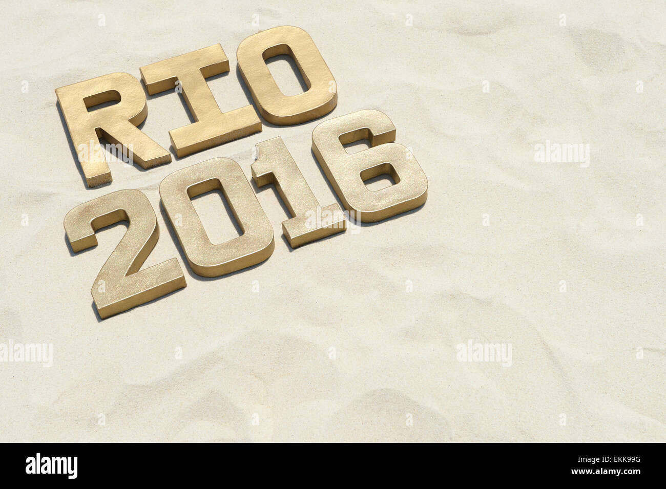 Golden Rio 2016 sign sitting on smooth sand beach background in Rio de ...