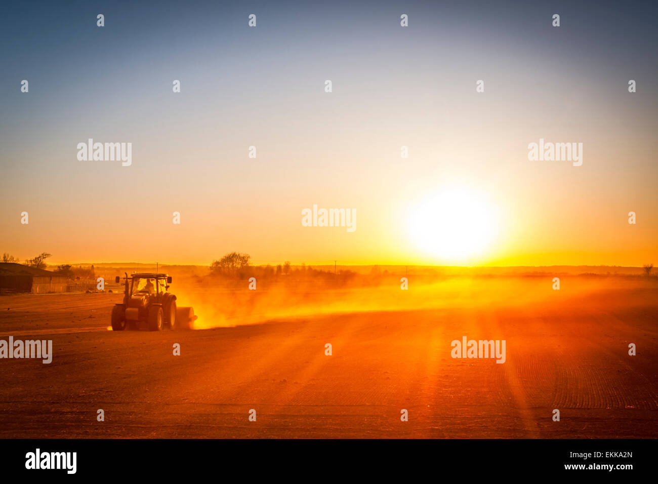 A farmer in a tractor prepares his field as the sun begins to set. The ...