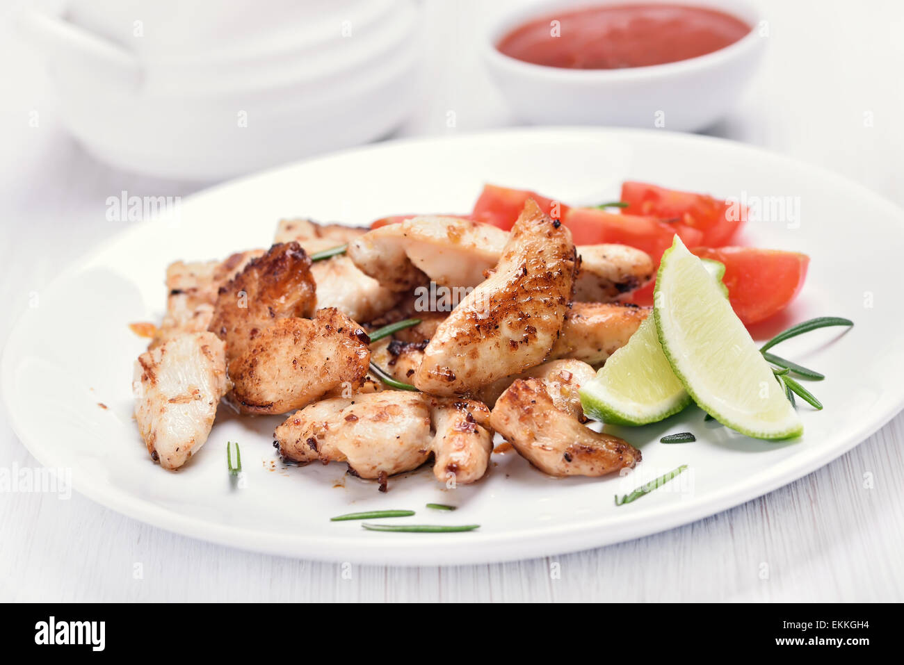 Cooked chicken sliced meat with vegetables on white plate, shallow ...