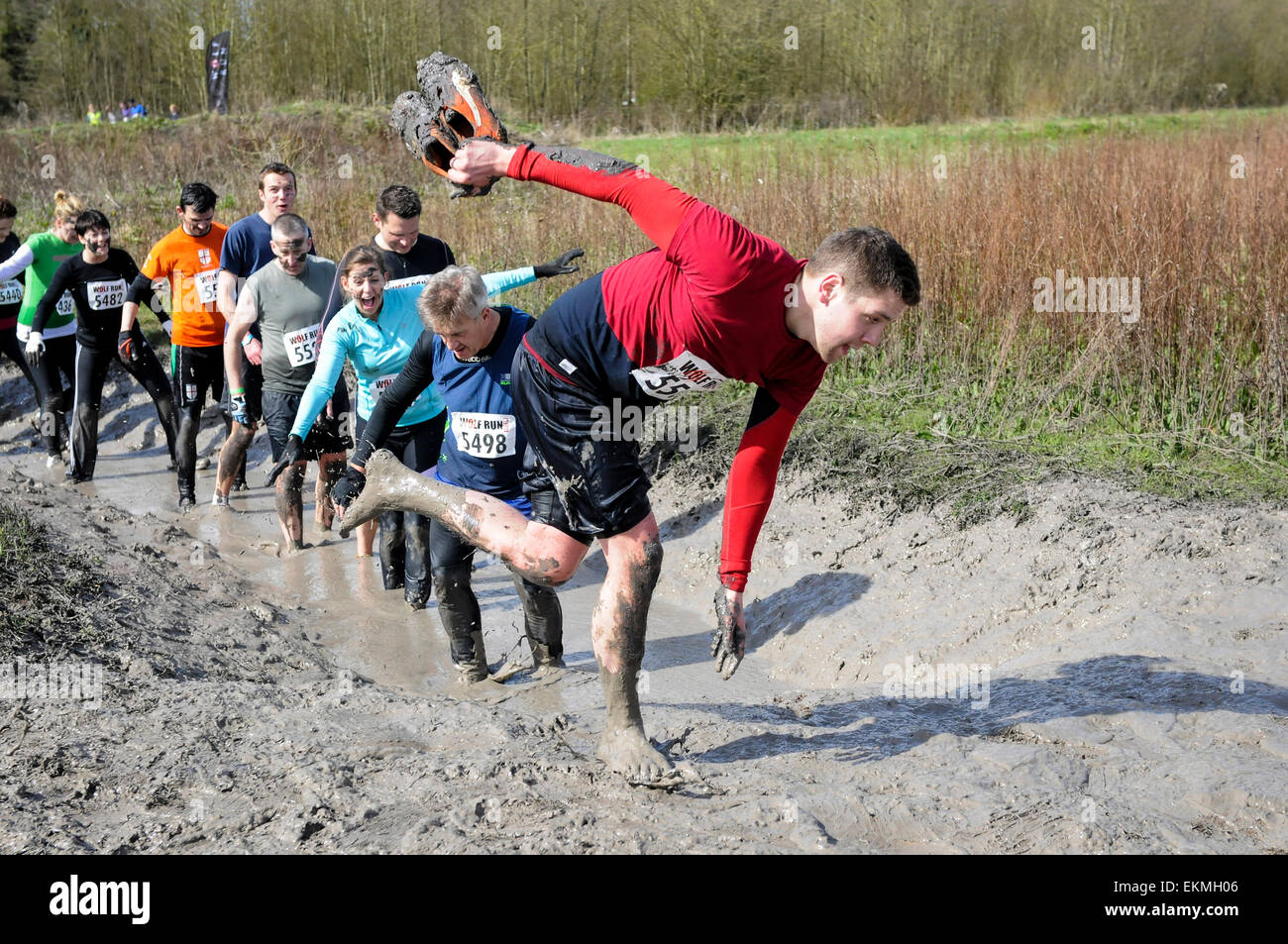 Mud covered runners trying to keep their balance at obstacle course ...