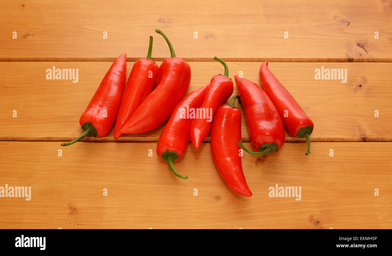 Eight sweet red baby peppers on a wooden table Stock Photo - Alamy