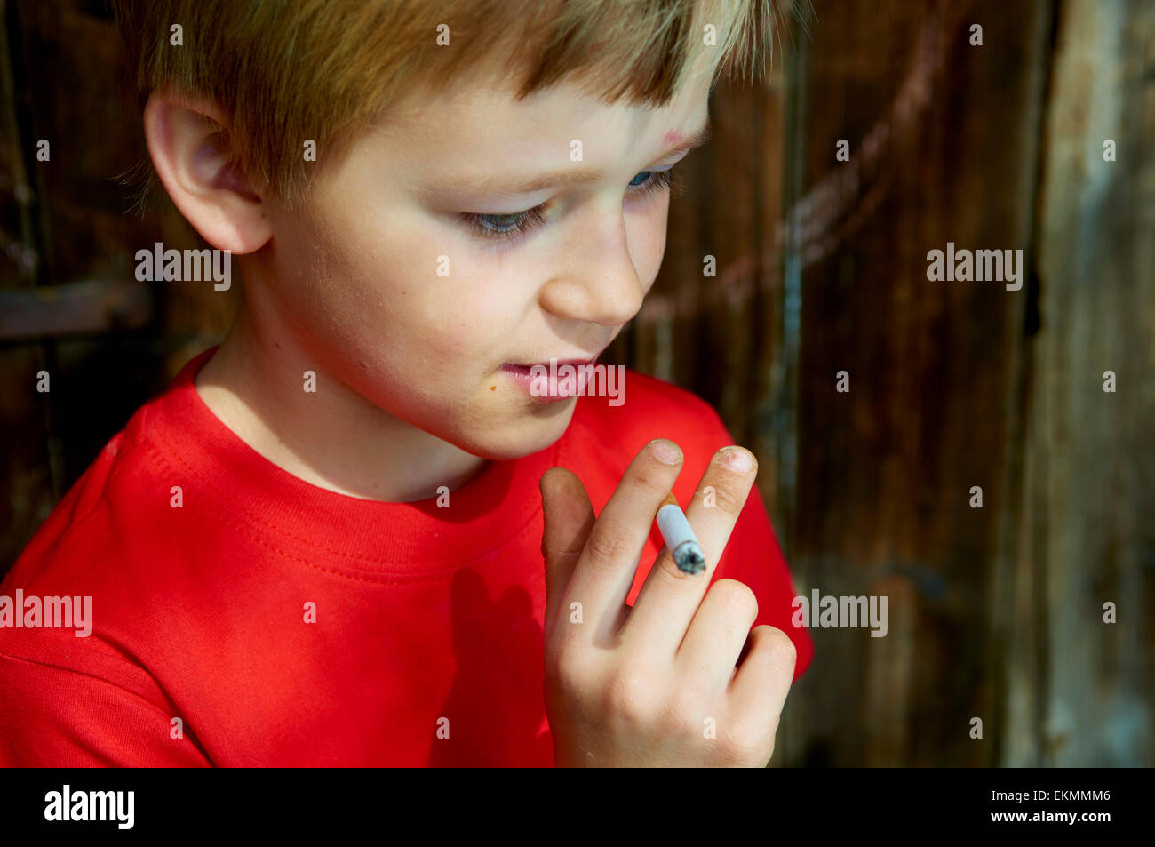 Portrait of Child blond boy smoking cigarette with dark wooden ...