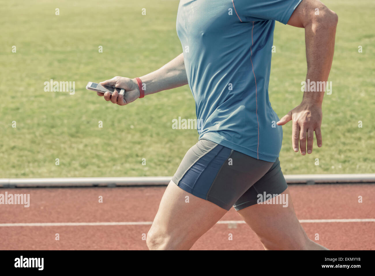 Runner in a stadium checks his fitness results on a smart phone while ...