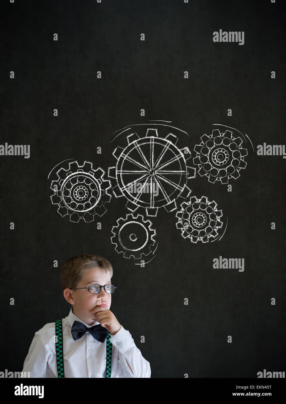 Thinking boy dressed as business man with chalk turning gear cogs or ...