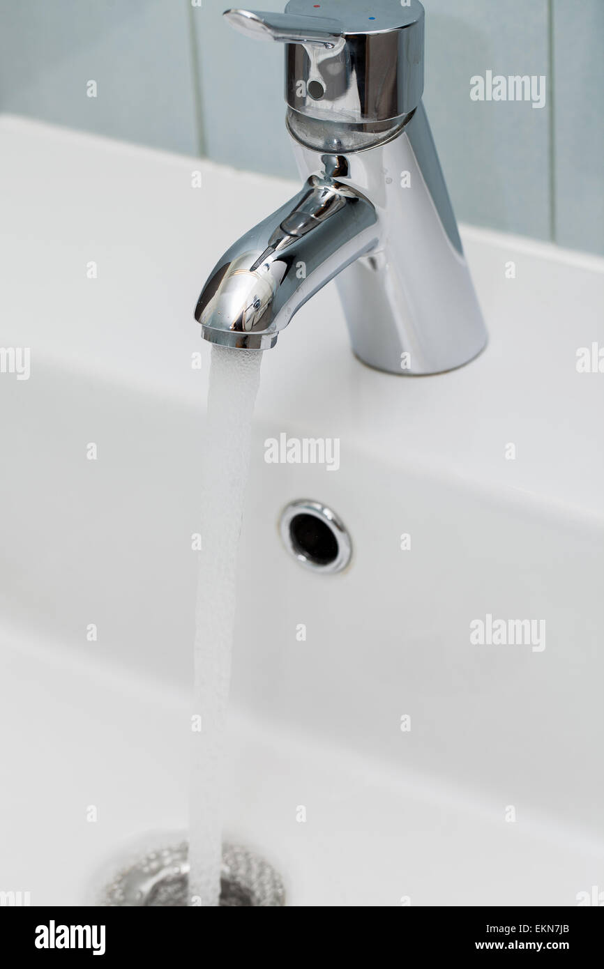 Tap with flowing water over the sink Stock Photo - Alamy