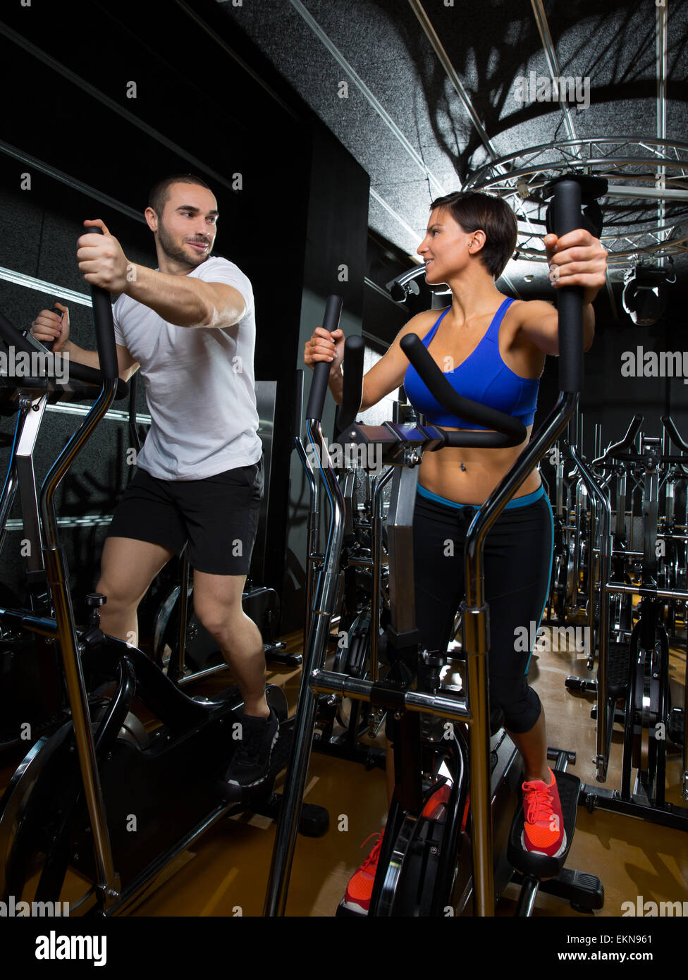 elliptical walker trainer man and woman at black gym Stock Photo - Alamy