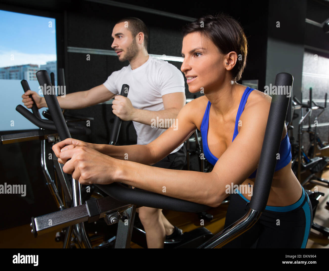 elliptical walker trainer man and woman at black gym Stock Photo - Alamy
