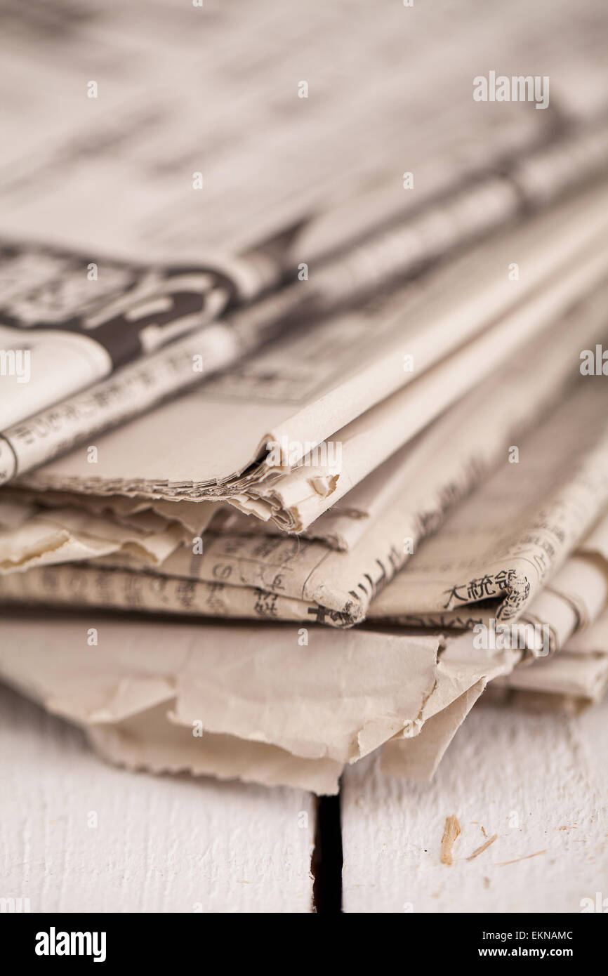 Pile of newspapers on a white table Stock Photo - Alamy