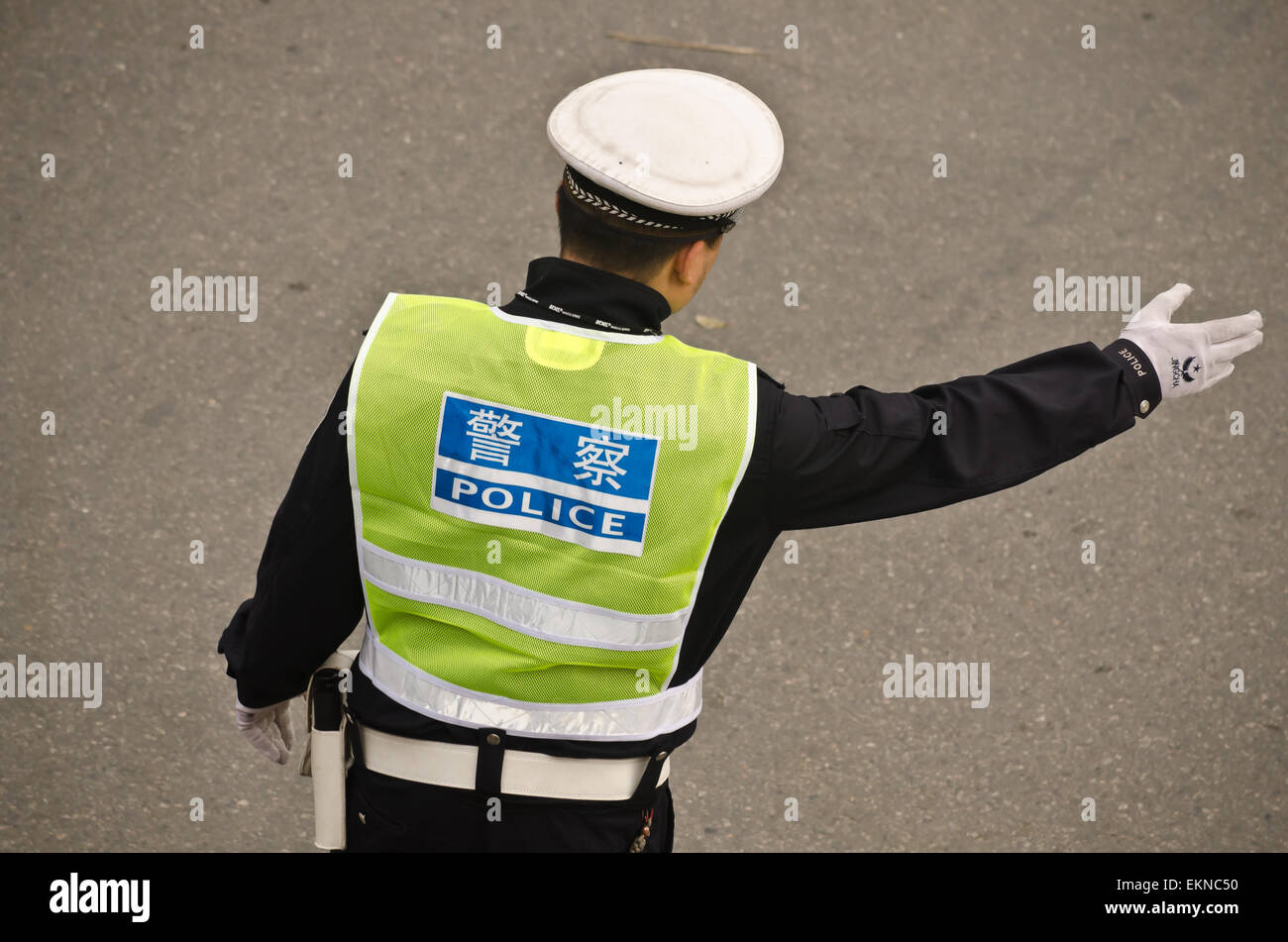 A young police officer directs traffic on a busy road at rush hour in ...