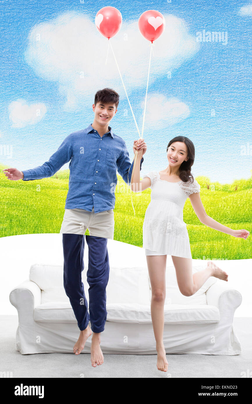 Happy young couple jumping with balloon Stock Photo - Alamy