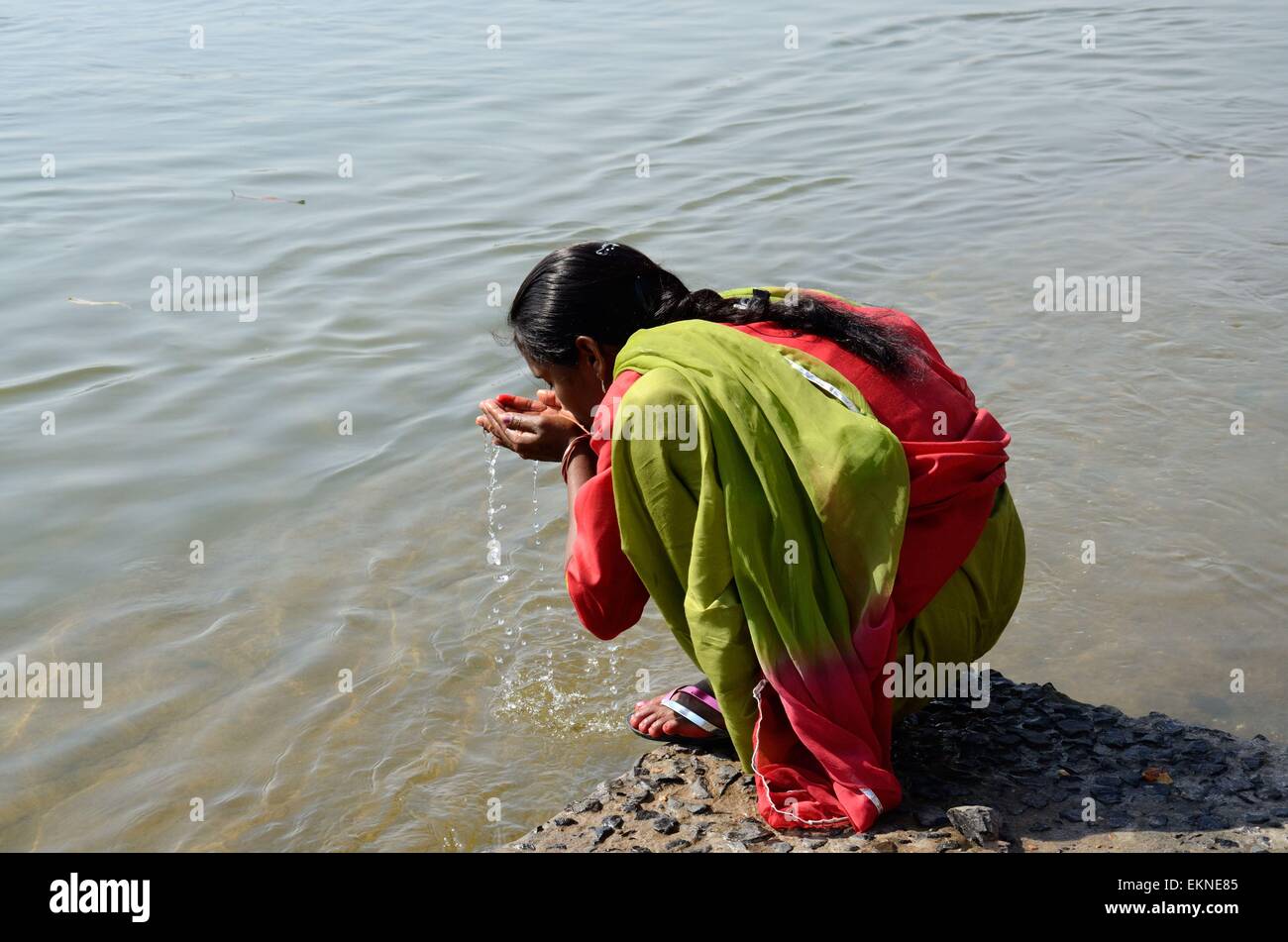 An Indian Hindu woman drinking river water from cupped hands Narbada ...