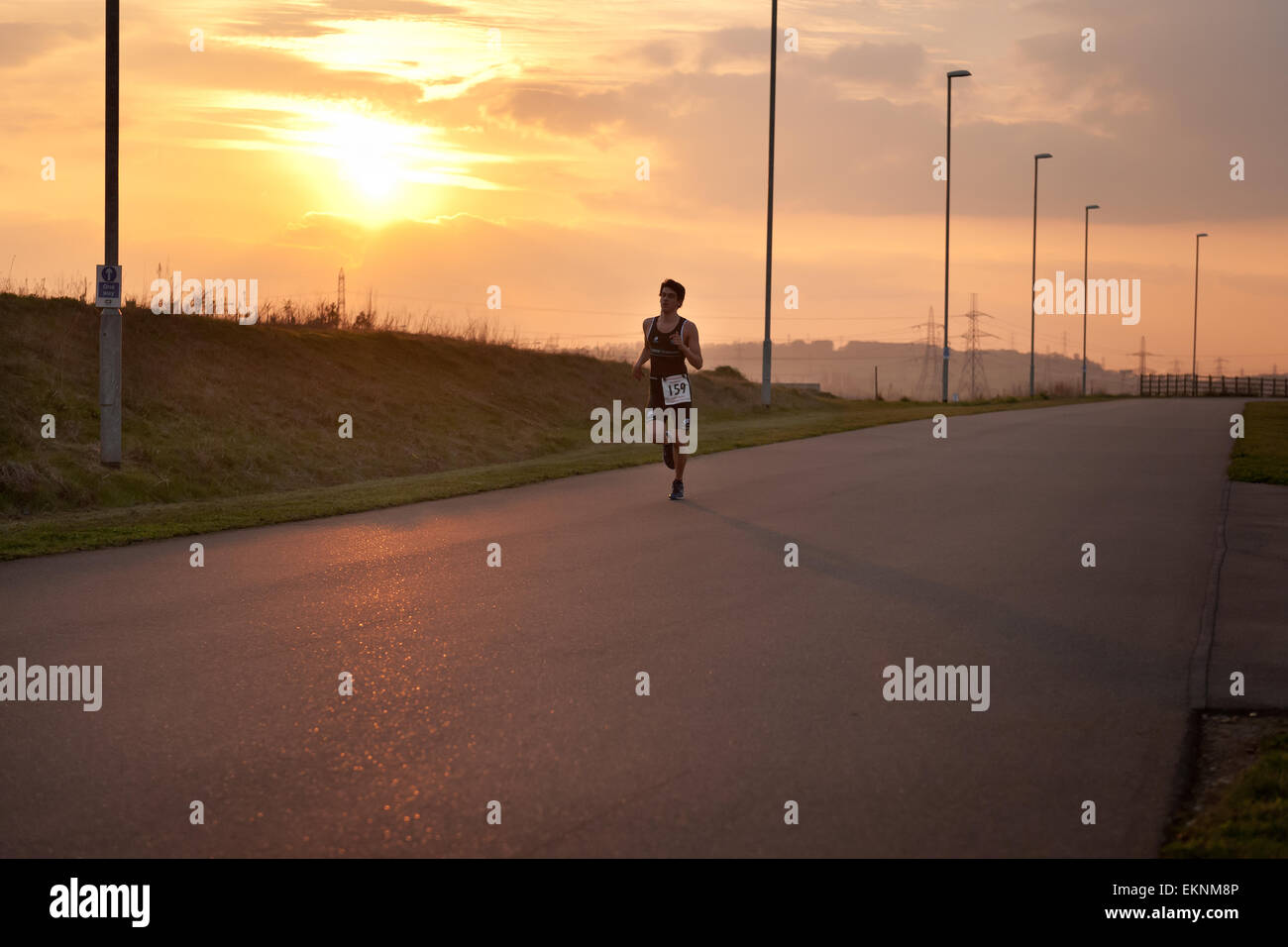 Teenager triathele running as part of a duathlon race with setting sun ...