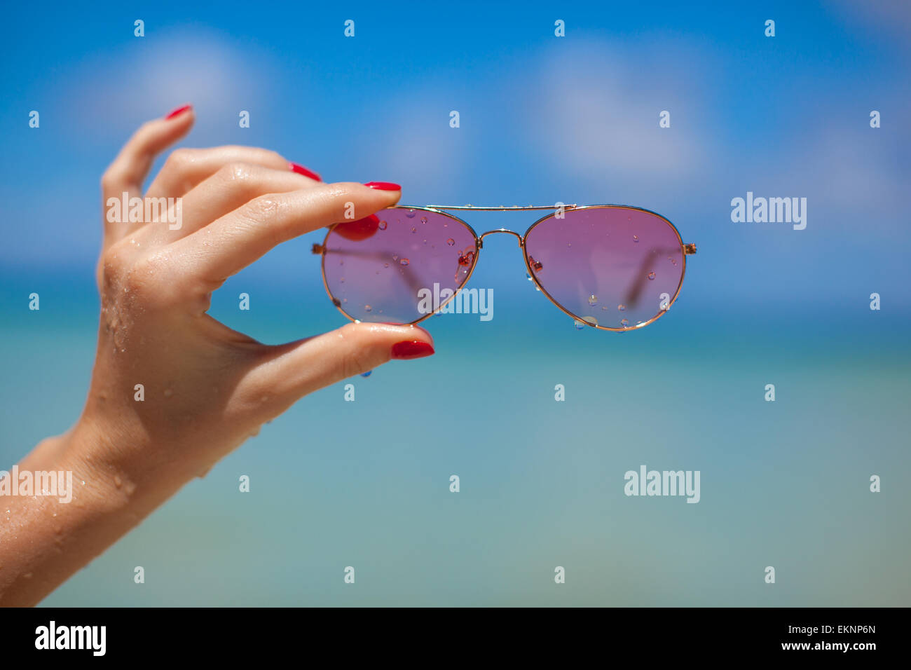 womans hand holding sunglasses on tropical beach Stock Photo - Alamy
