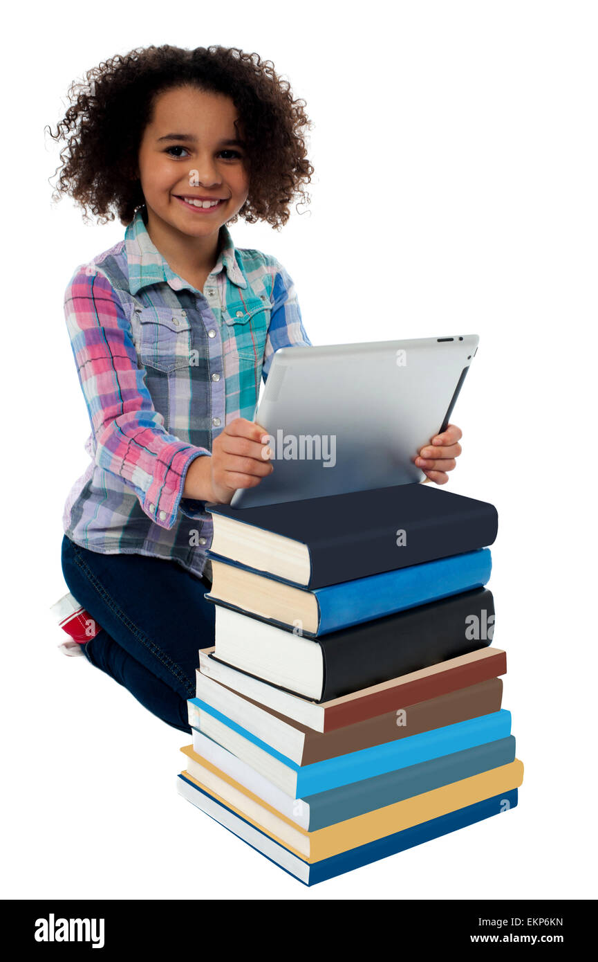 Smiling child busy with tablet pc and books Stock Photo - Alamy