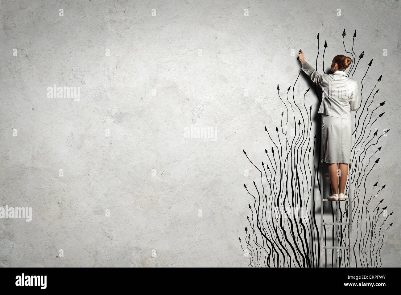 Woman standing on ladder drawing on wall Stock Photo - Alamy