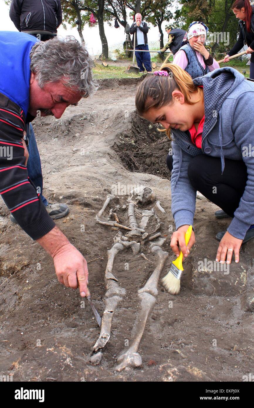 Archaelogists inspects a grave with a skeleton with an iron rod ...