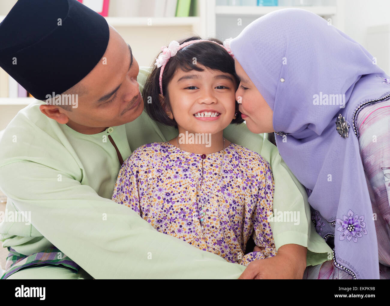 Muslim parents kissing child Stock Photo - Alamy