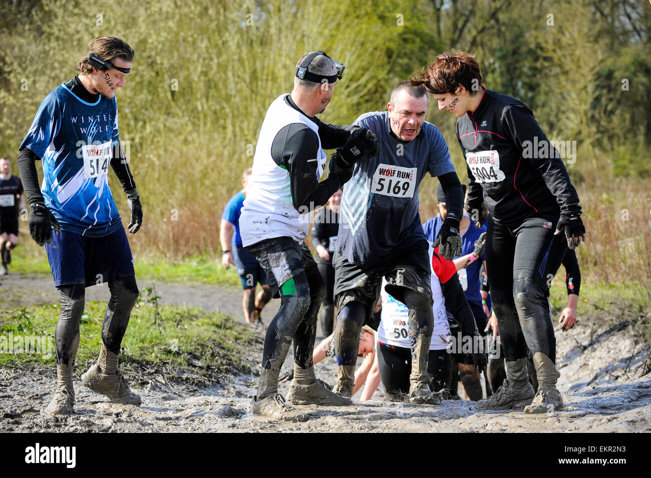 Mud covered runners helping an older male runner out of a slippery ...