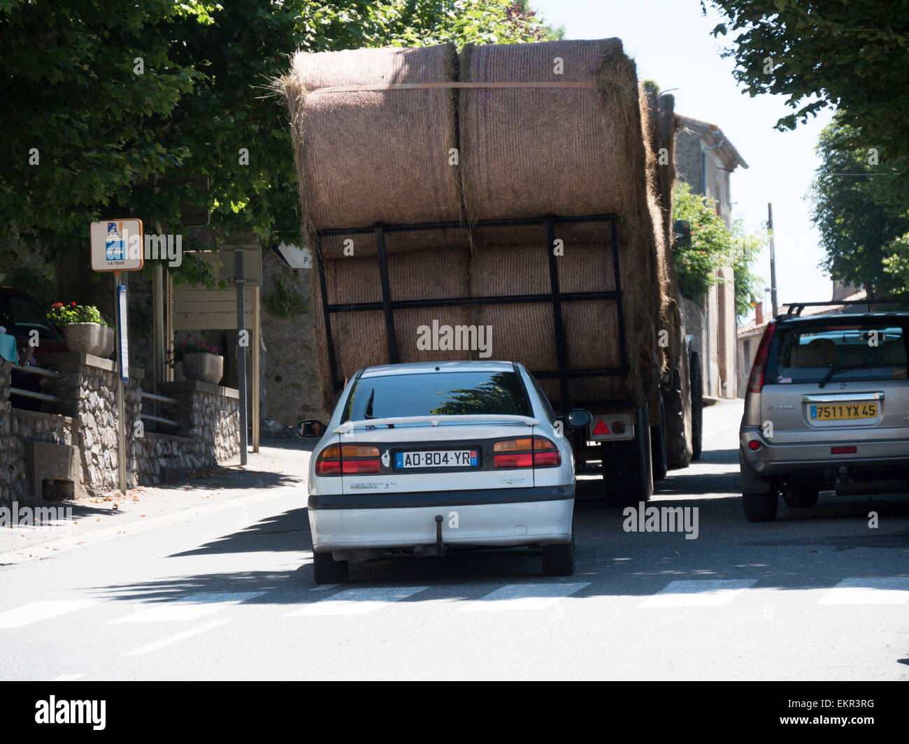 A car follows a farm tractor loaded with stray bales through a village ...