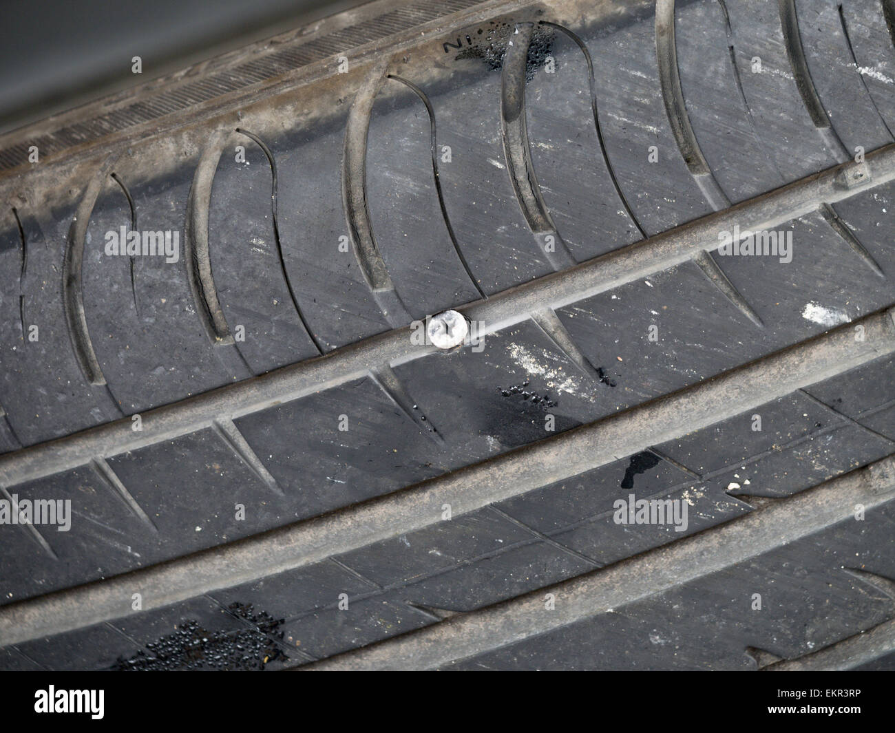 A nearly new car tyre punctured by a deeply embedded screw Stock Photo ...