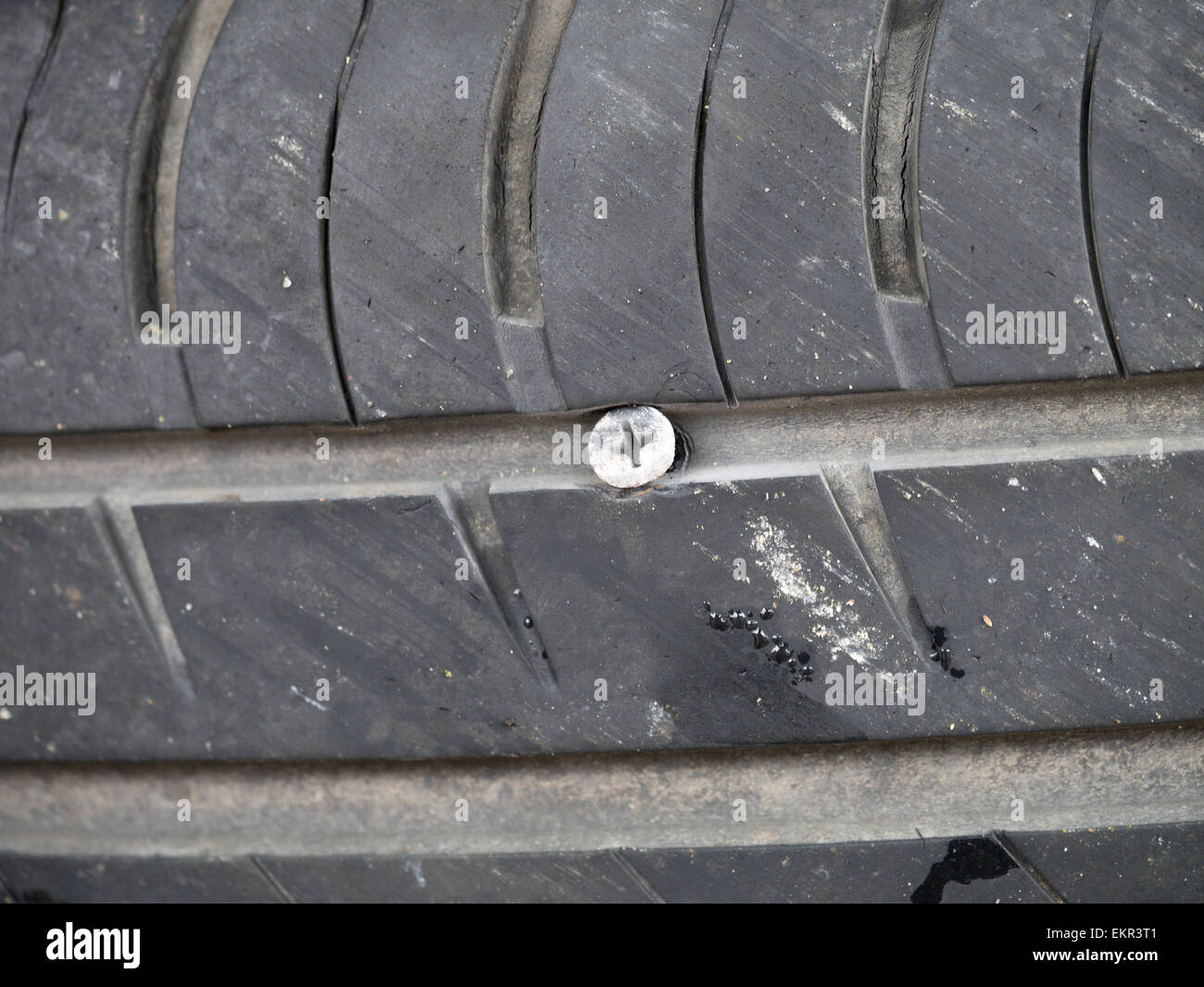 A nearly new car tyre punctured by a deeply embedded screw Stock Photo ...