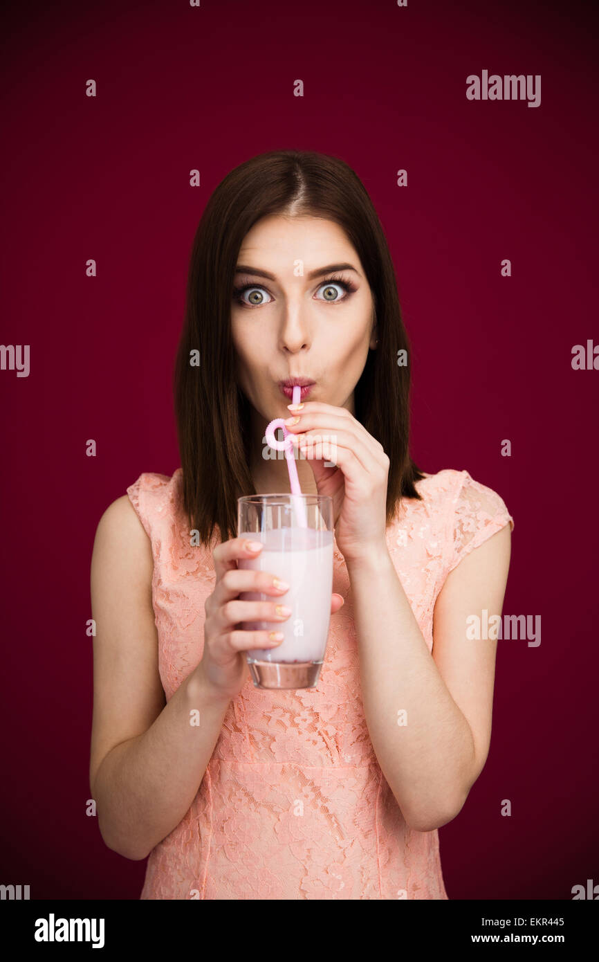 Young pretty woman drinking yogurt over pink background and looking at ...
