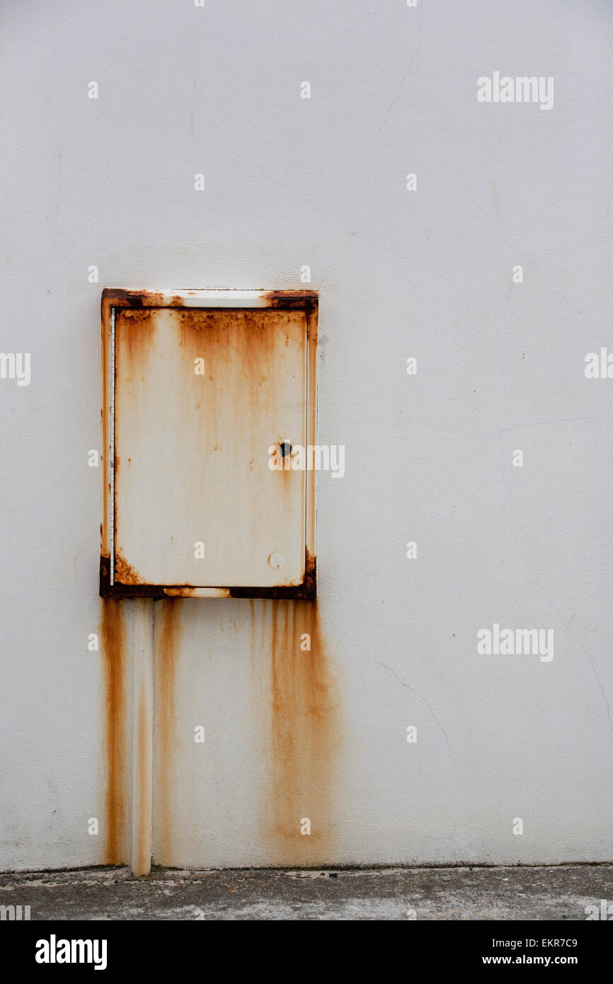 A wall mounted metal box with rust stains down the wall Stock Photo - Alamy